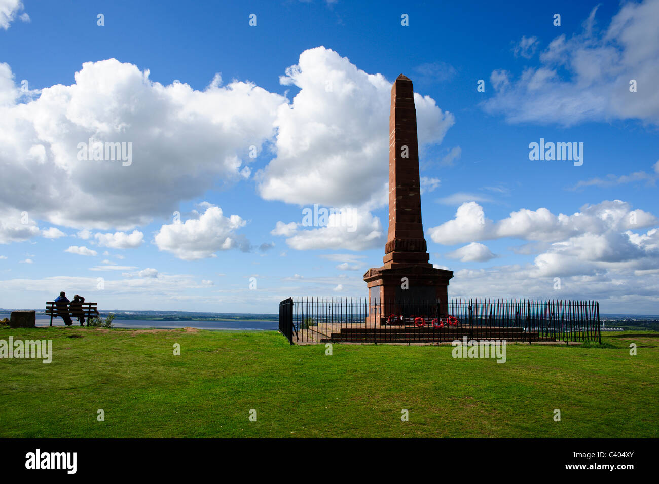 A couple sit on a bench next to Frodsham War Memorial on a hill ...
