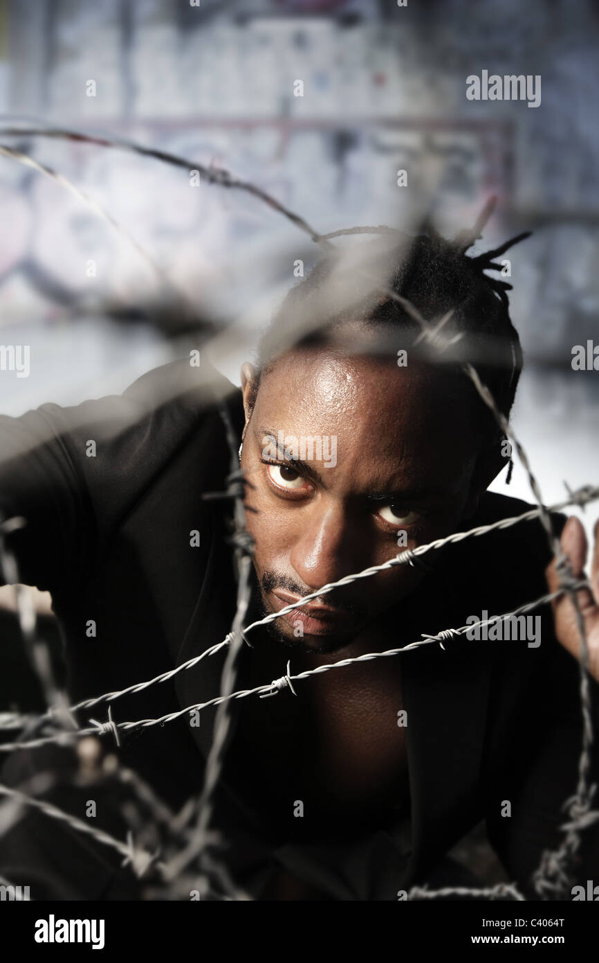 Portrait of a man holding barbed wire and a graffiti wall in background ...
