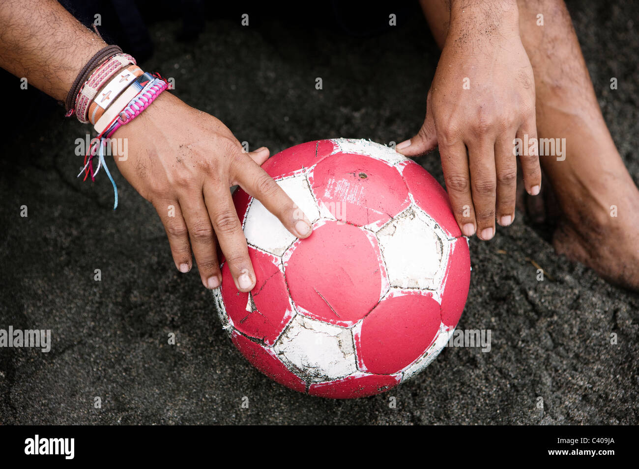 Hands on red football in sand Stock Photo - Alamy