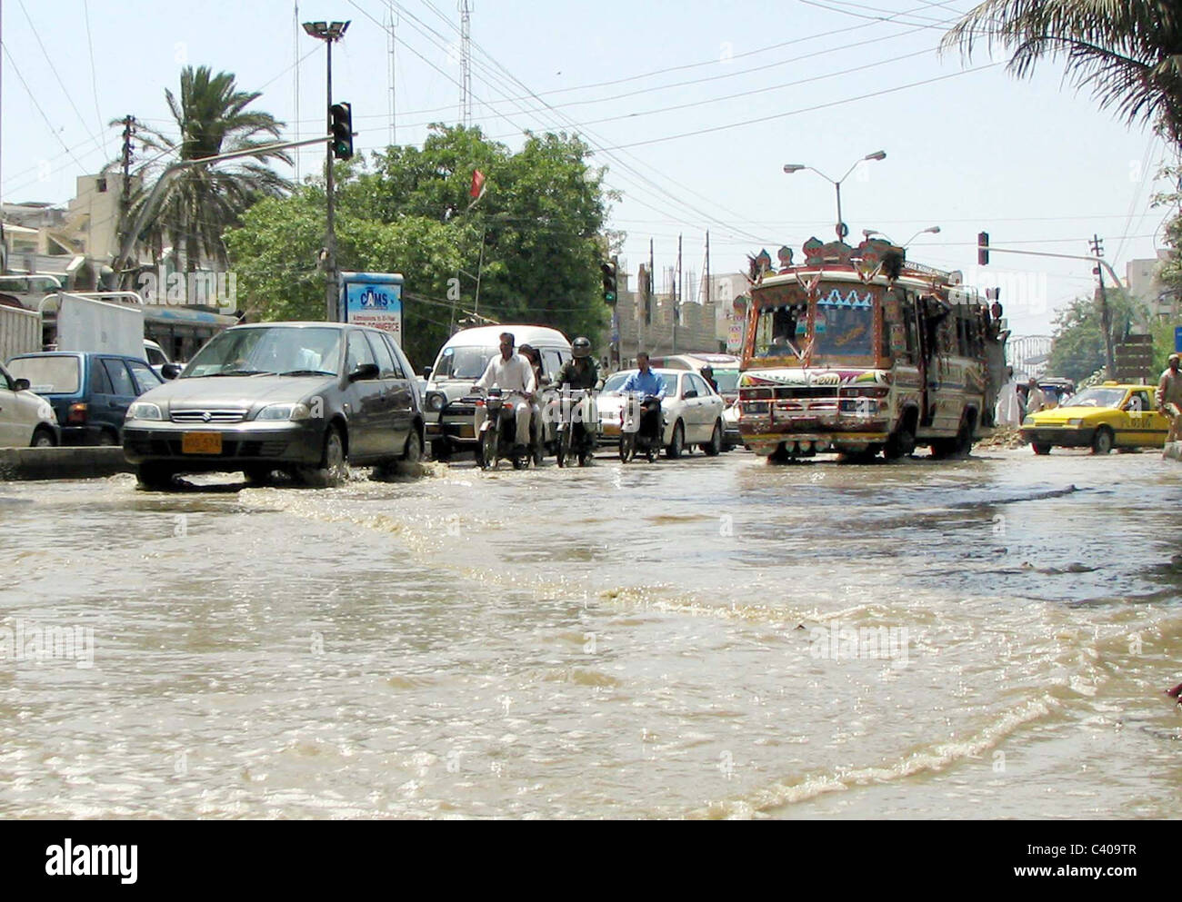 Motorists pass through sewerage water that stands at a road which is ...