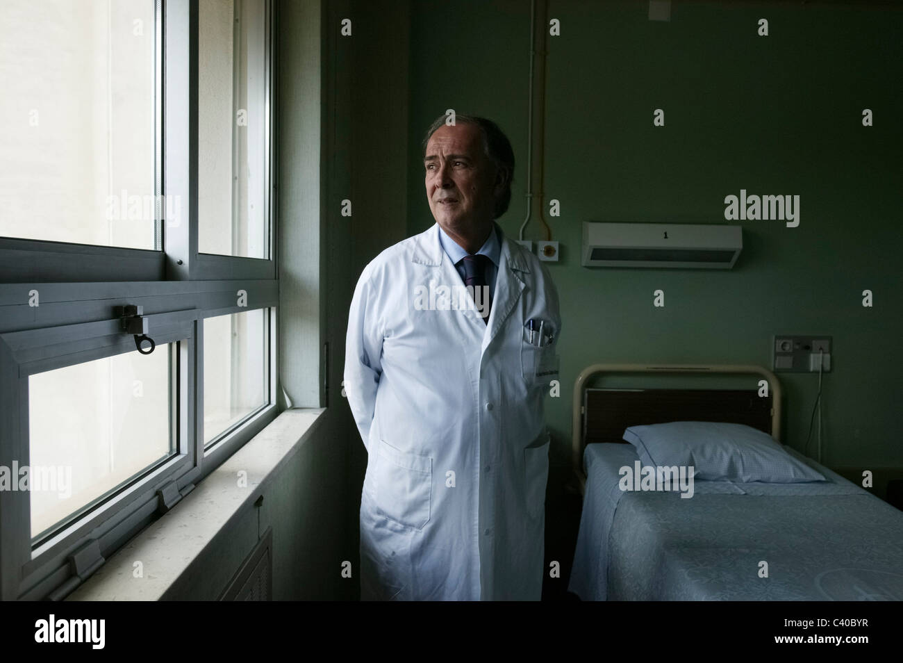 Portrait of worried doctor looking out the window in an hospital ward ...