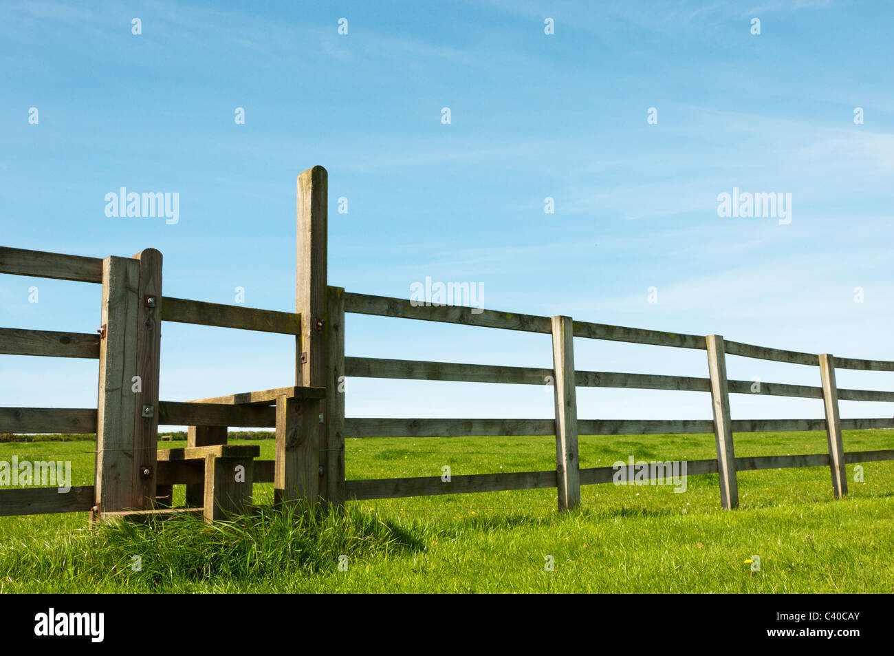 A wooden stile in a farm fence seen against a clear blue sky Stock ...