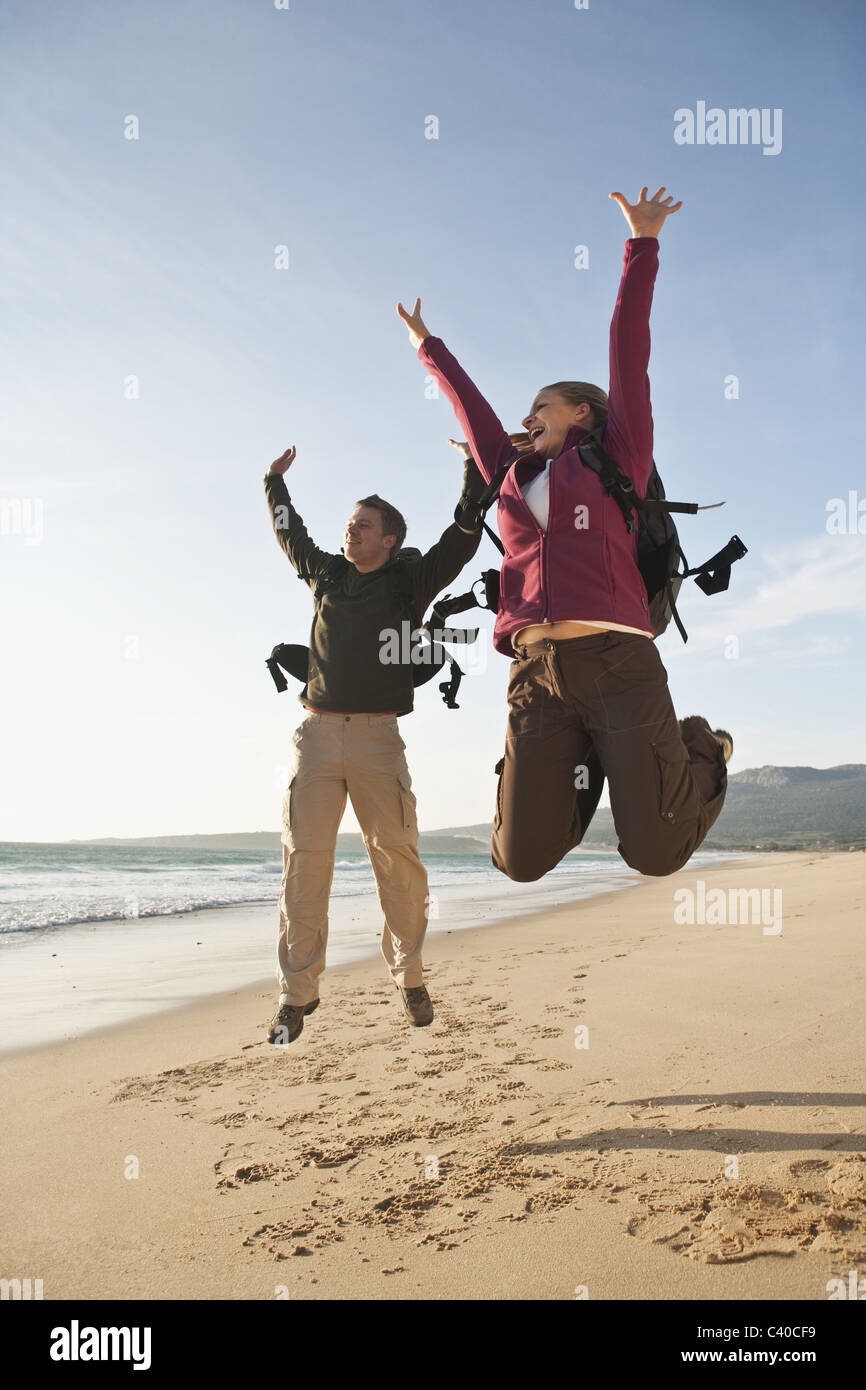Young backpackers jumping on beach Stock Photo - Alamy