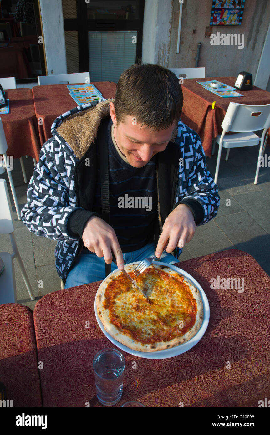Russian man in his 30s eating pizza in Castello district Venice Italy ...