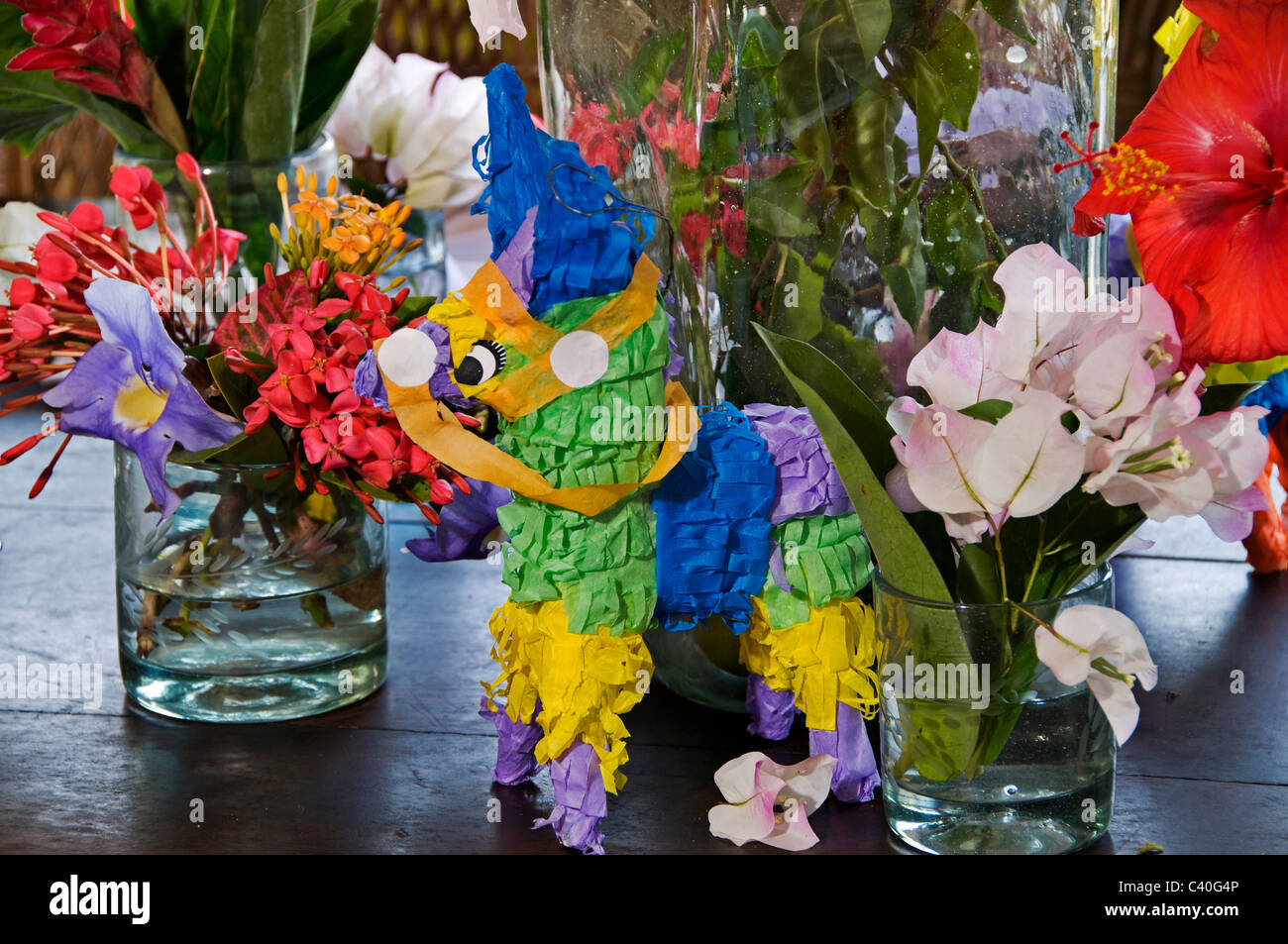 Vases of tropical flowers and a colorful pinata adorn this table for a ...