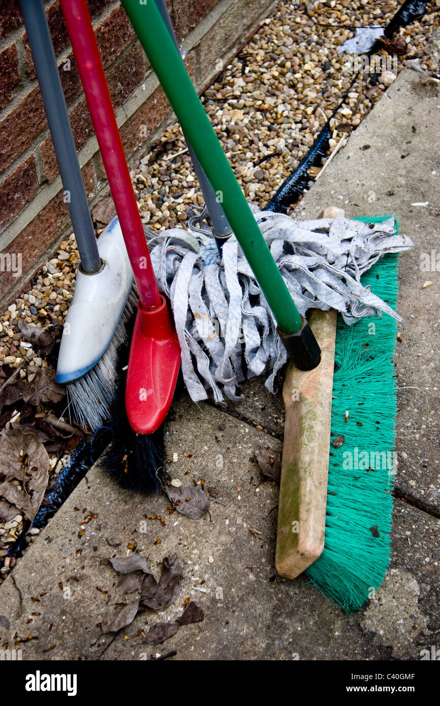 Three brooms and a mop Stock Photo - Alamy