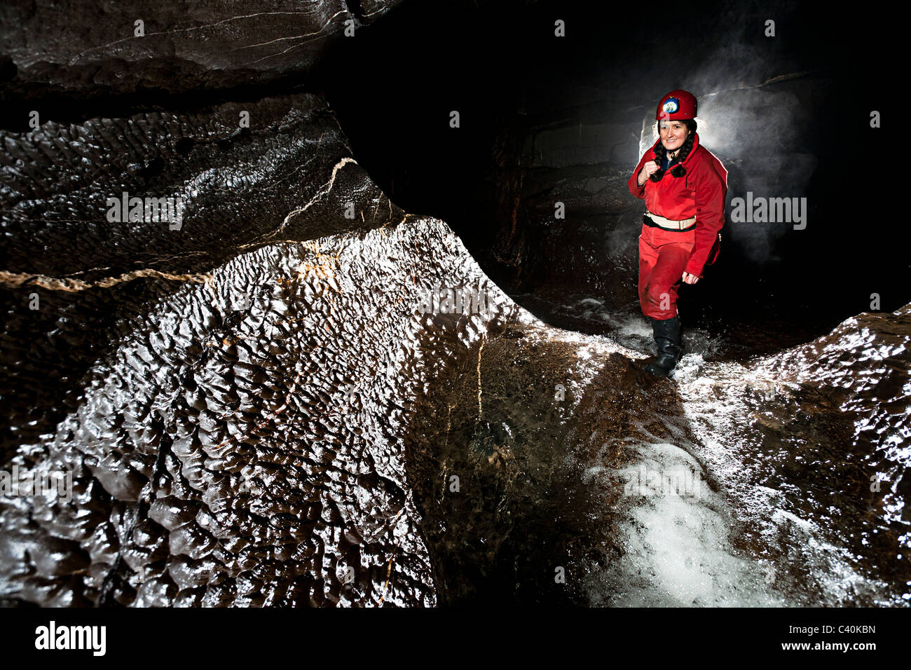 Female caver in cave river passage with scallop marks on walls Wales UK ...