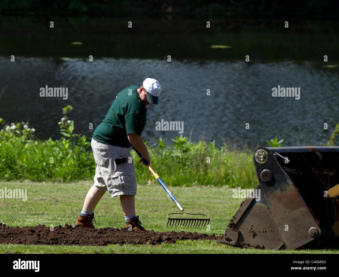 A woman raking out topsoil next to a lake Stock Photo - Alamy