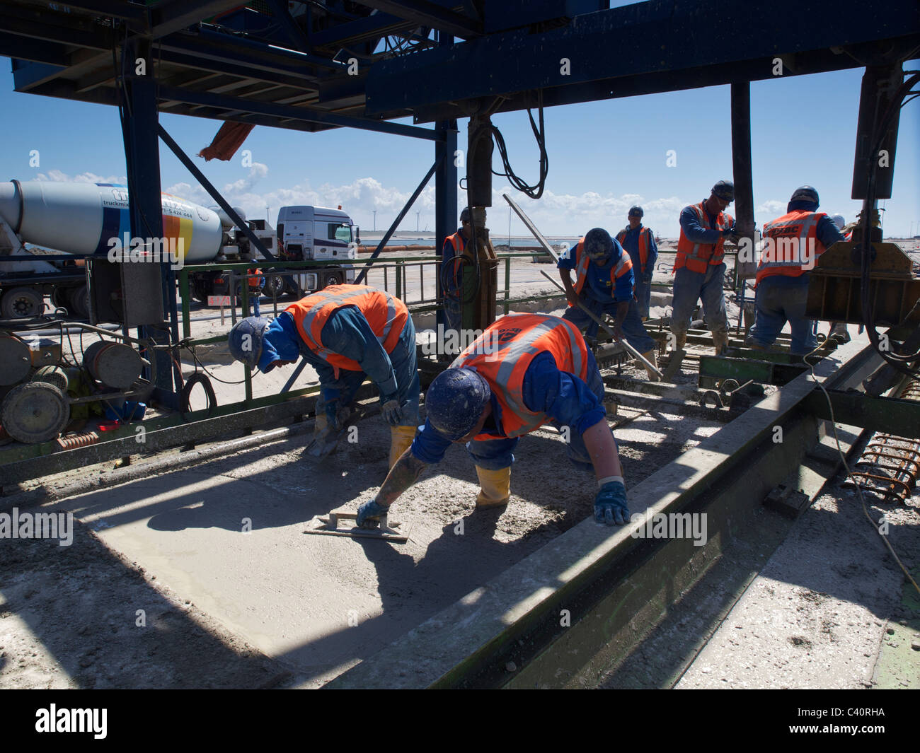 Workers pouring concrete making a new quay of the deep sea port ...