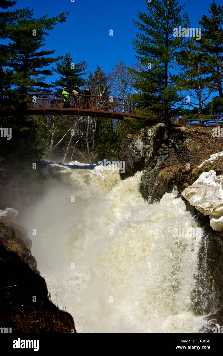 Group standing on bridge over seven raging waterfalls Maskinongé river ...