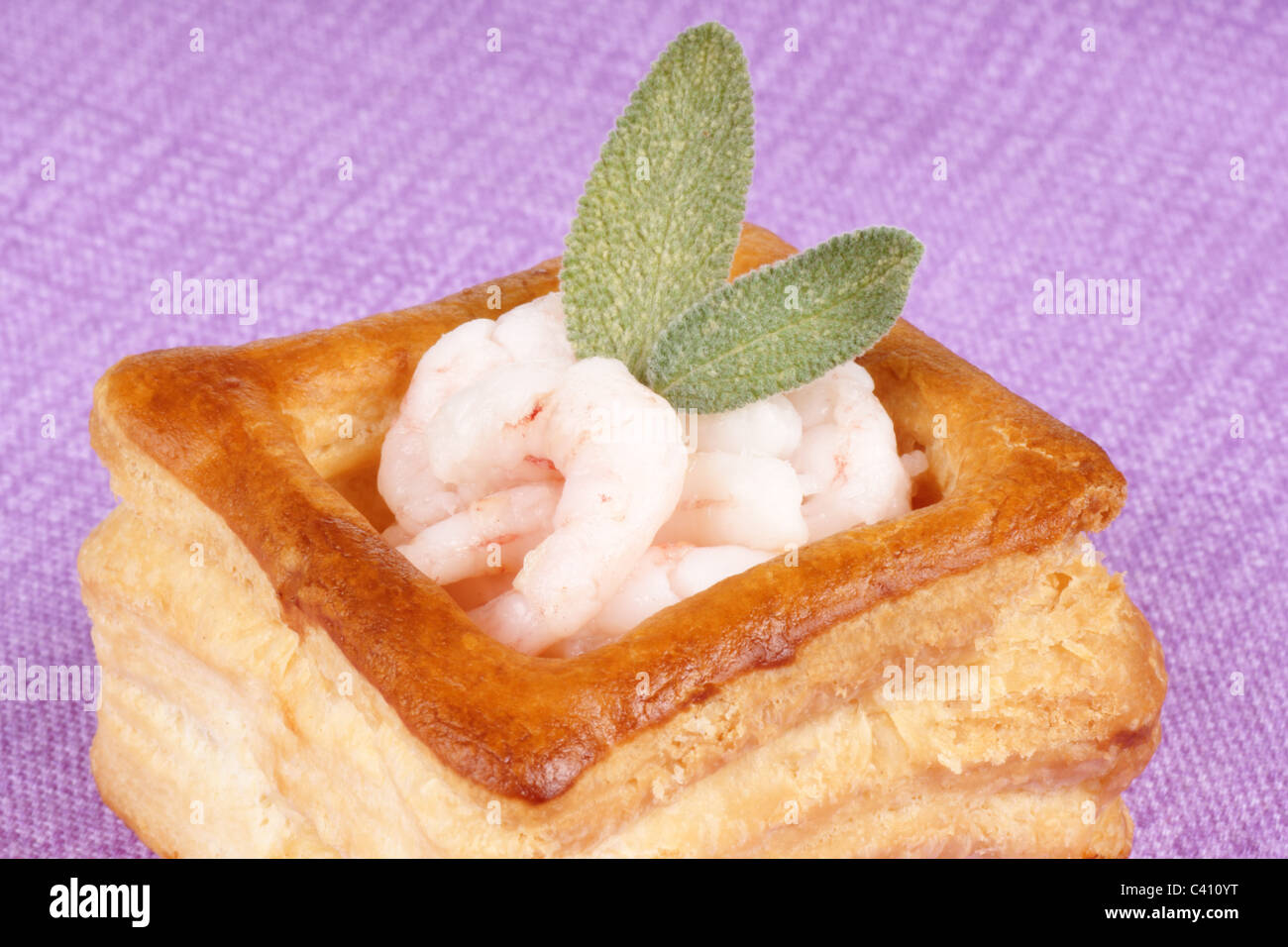 Close-up of a vol-au-vent with small boiled shrimps decorated with sage ...