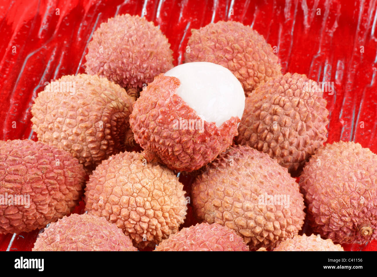 Close-up of some litchis (lychee) on a glass plate over a red ...
