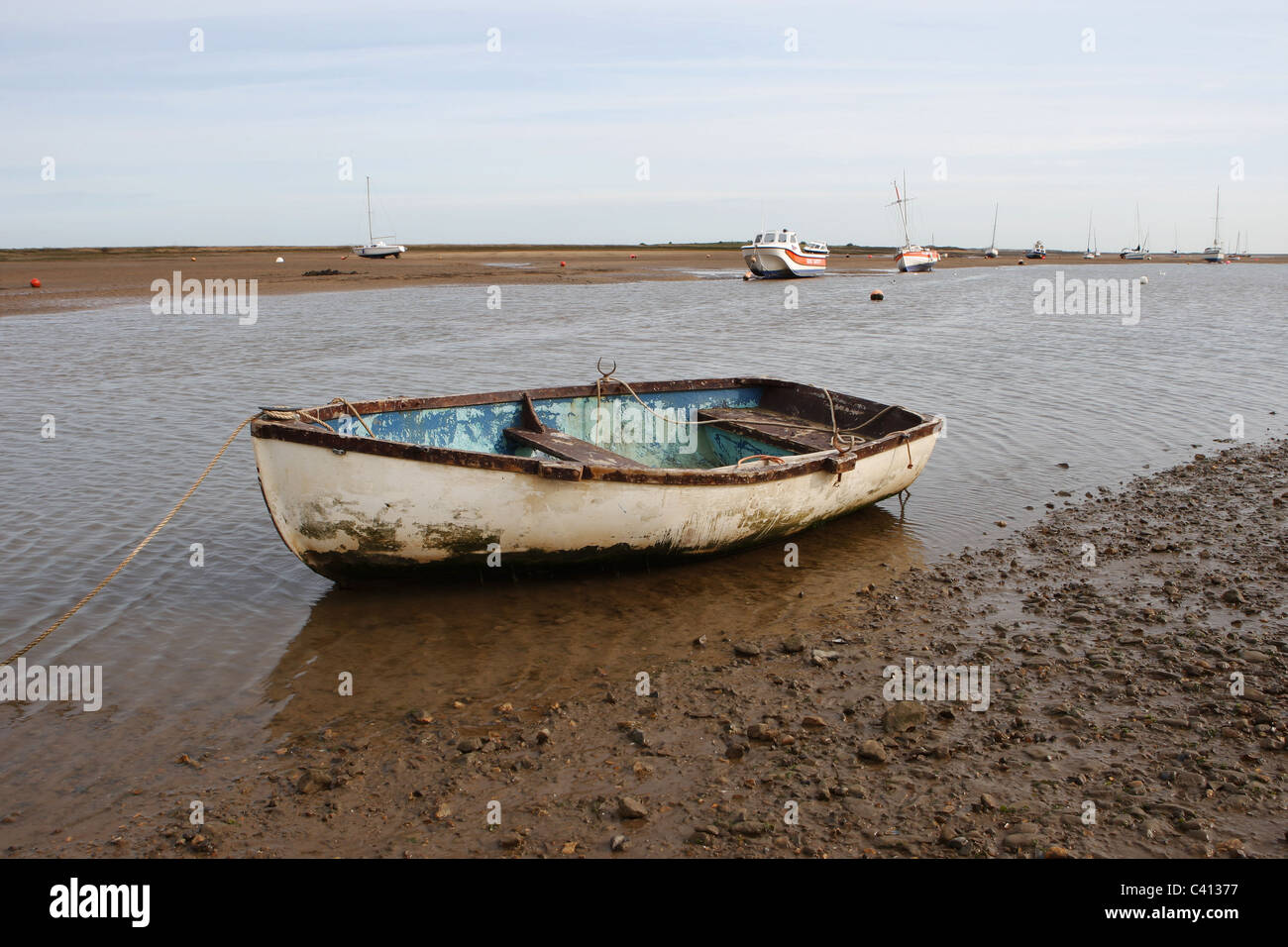 A beached rowing boat, fishing boat in the mudflats at Brancaster ...