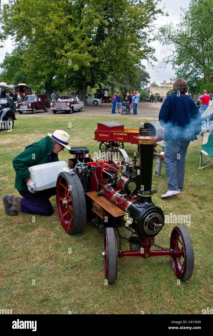 A man pouring water into a miniature steam traction engine Stock Photo ...