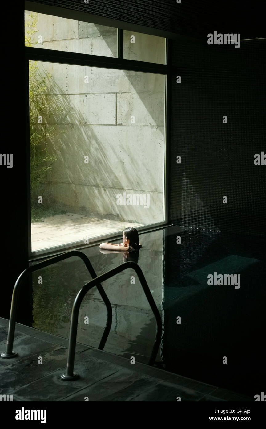 Woman looking out the window of an indoor swimming pool Stock Photo - Alamy