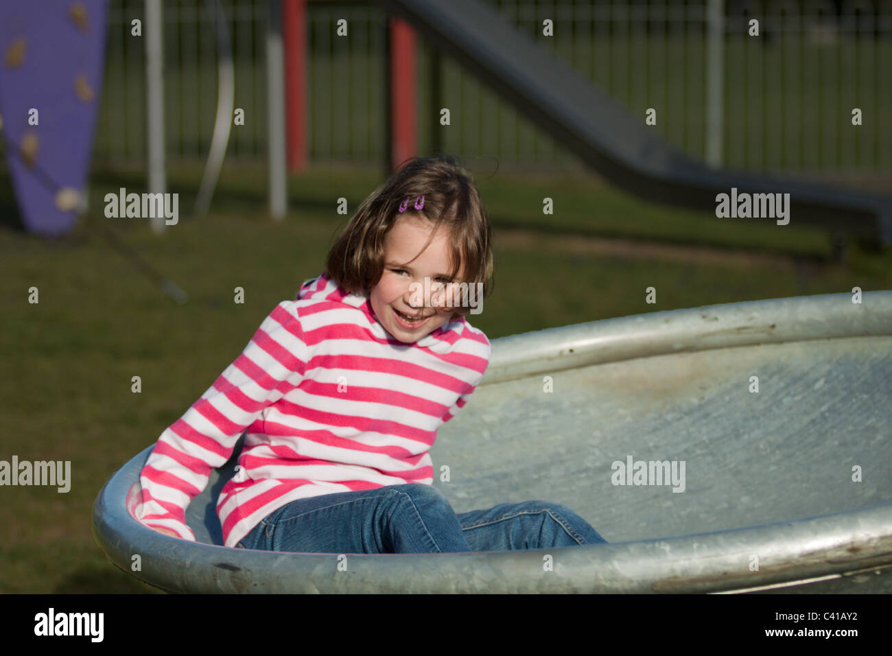 Young girl playing on roundabout at local park Stock Photo - Alamy
