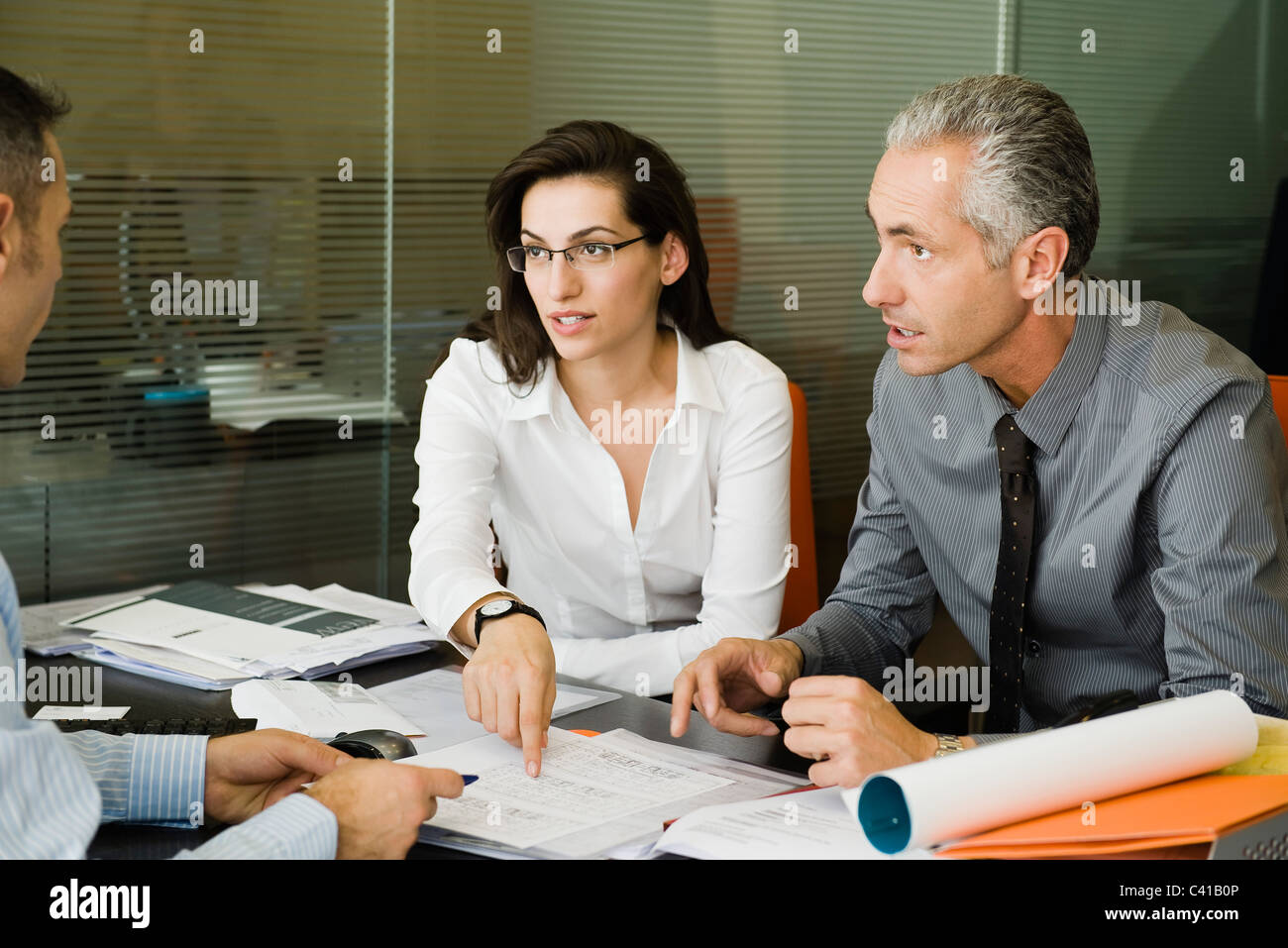 Clients discussing paperwork with businessman Stock Photo - Alamy