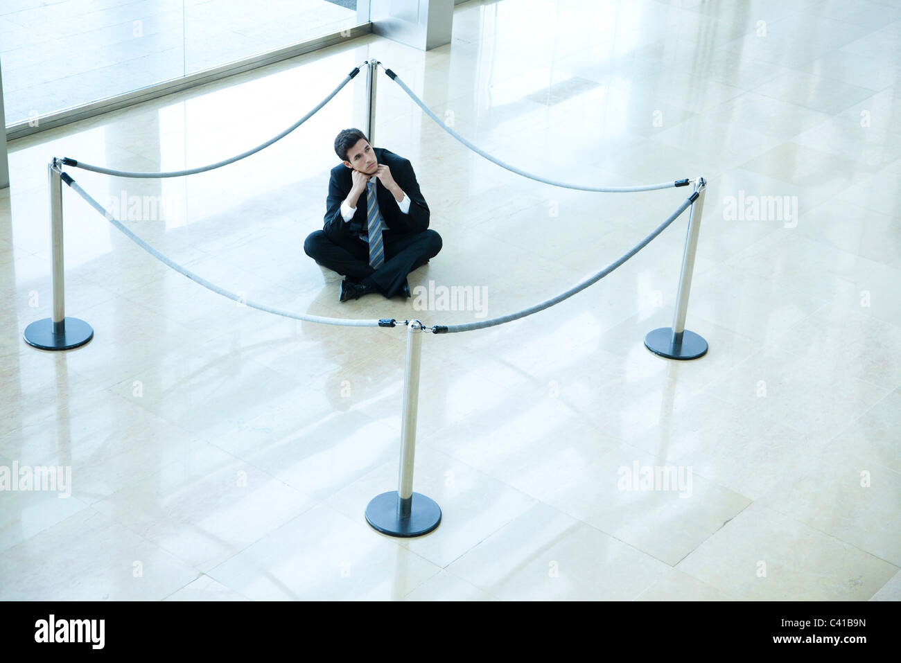 Businessman sitting on floor inside roped off area in lobby Stock Photo ...