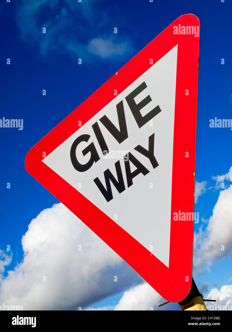 Give Way triangular warning sign on a UK road with blue sky and white ...