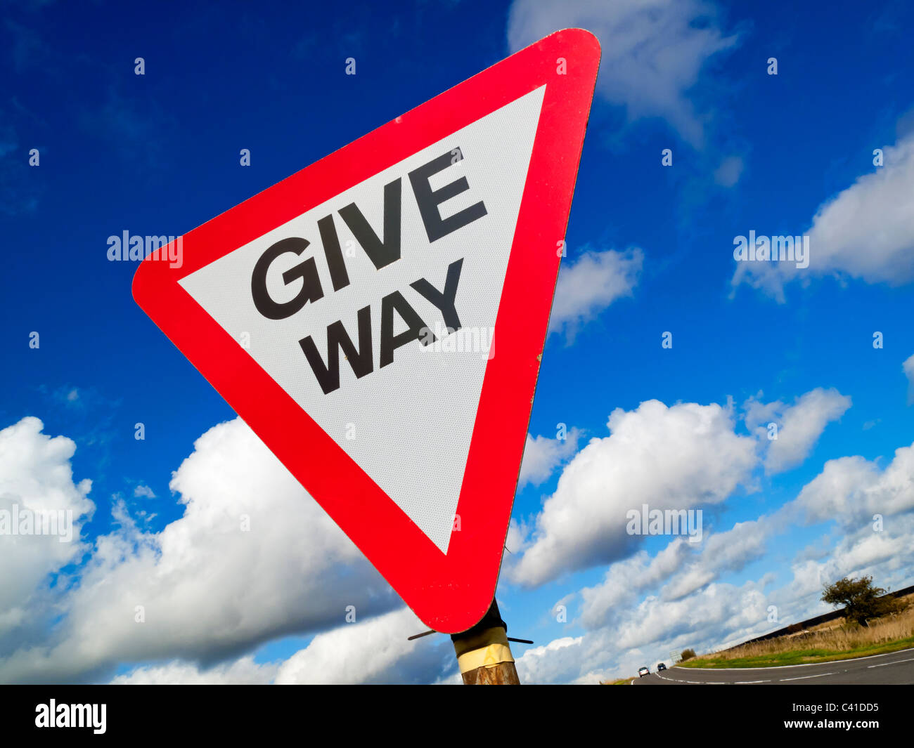 Give Way triangular warning sign on a UK road with blue sky and white ...