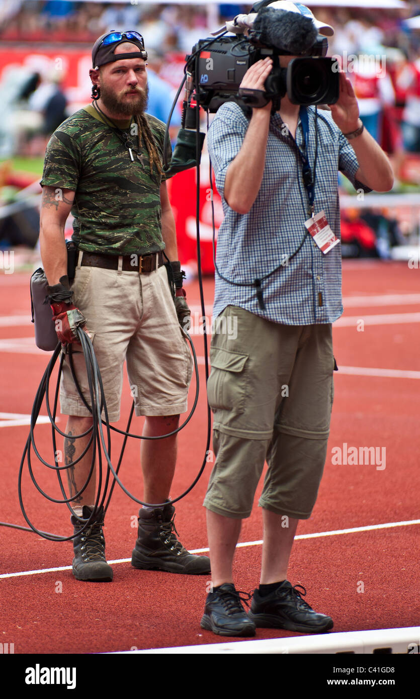 High resolution image of a TV cameraman and his pierced helper at sport ...
