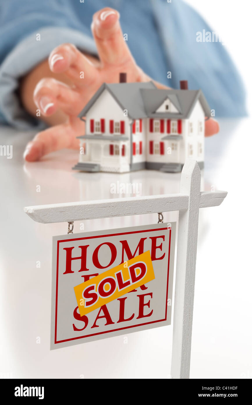 Sold Real Estate Sign in Front of Woman's Hand Reaching for Model House ...