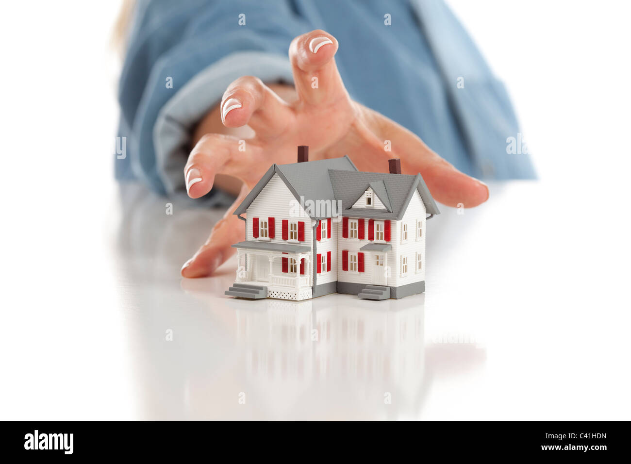 Woman's Hand Reaching for Model House on a White Surface Stock Photo ...