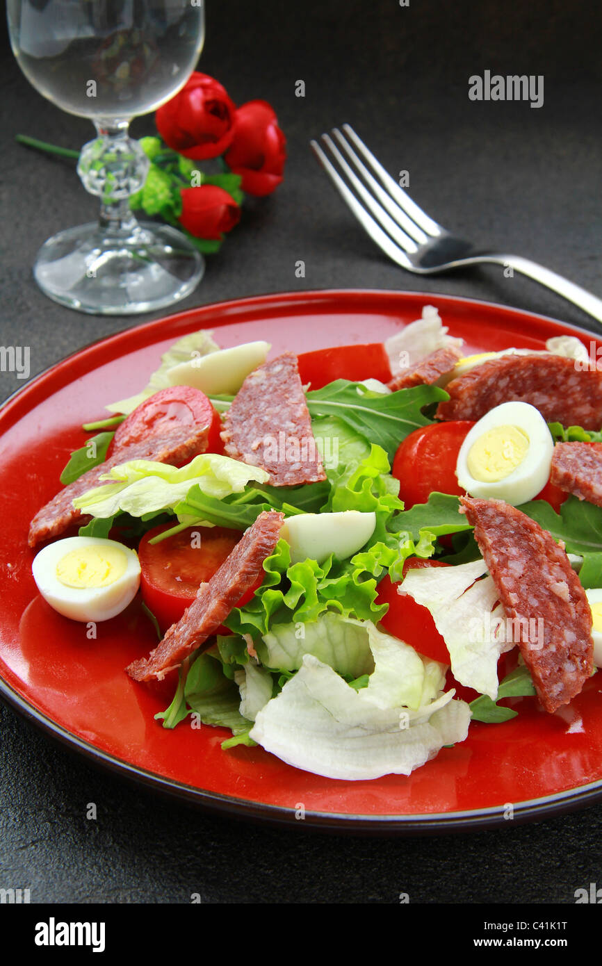 salad with quail eggs and salami on a red plate Stock Photo - Alamy