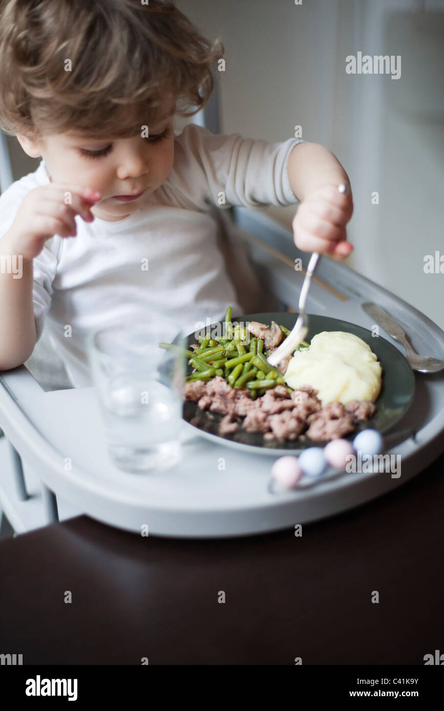 Toddler boy feeding himself Stock Photo - Alamy