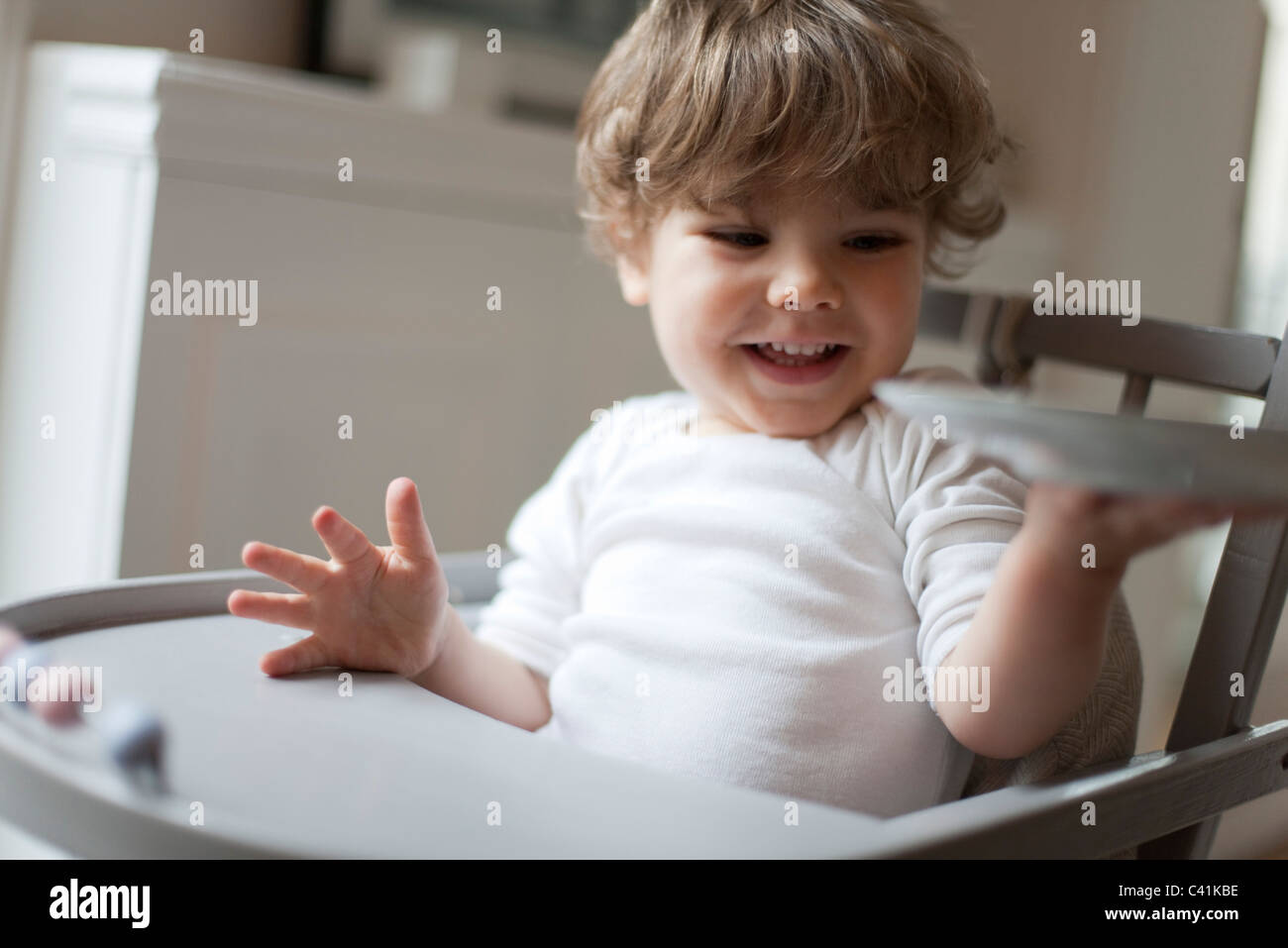 Toddler boy sitting in high chair at snacktime Stock Photo - Alamy