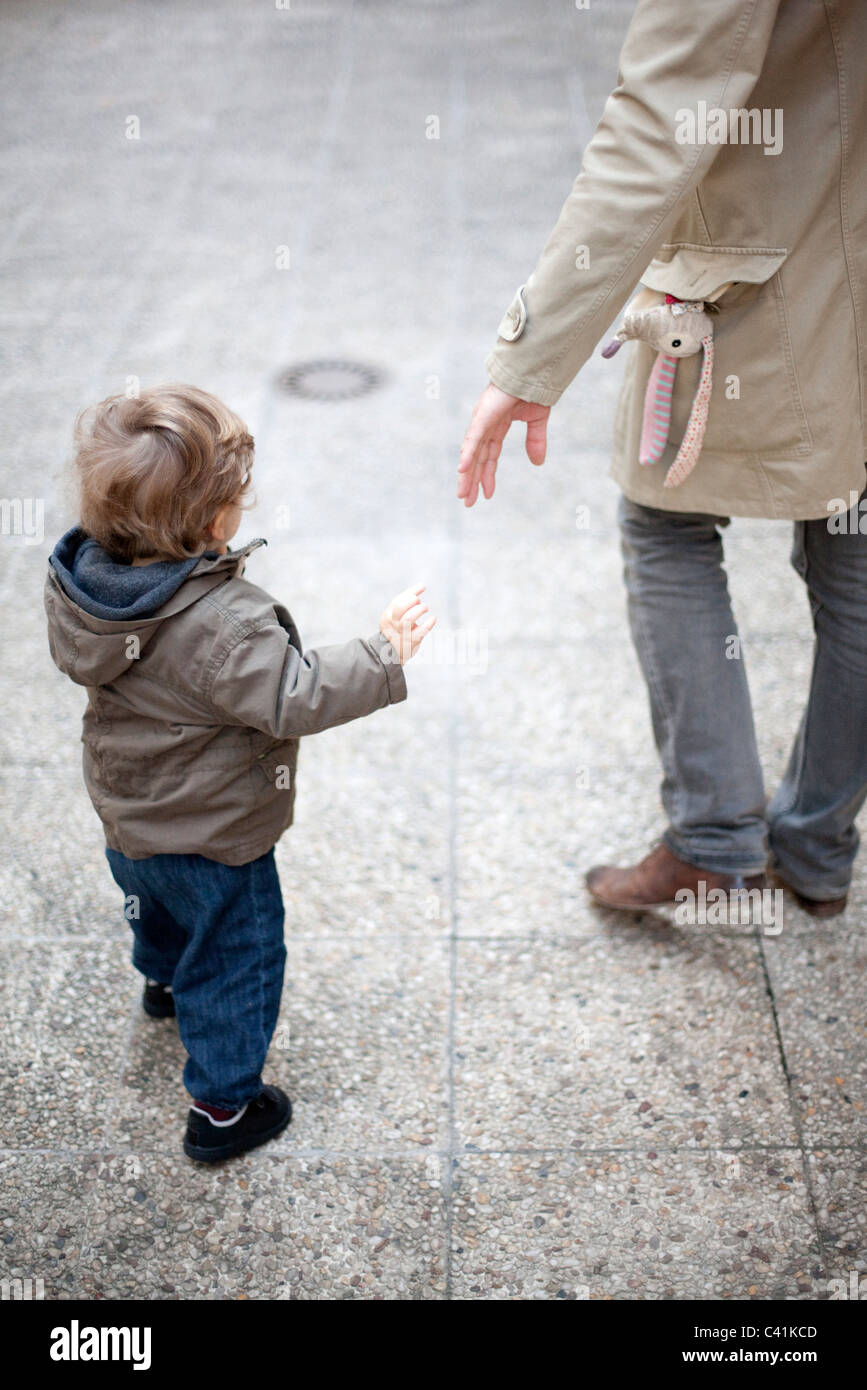Father reaching for toddler's hand on sidewalk, cropped Stock Photo - Alamy