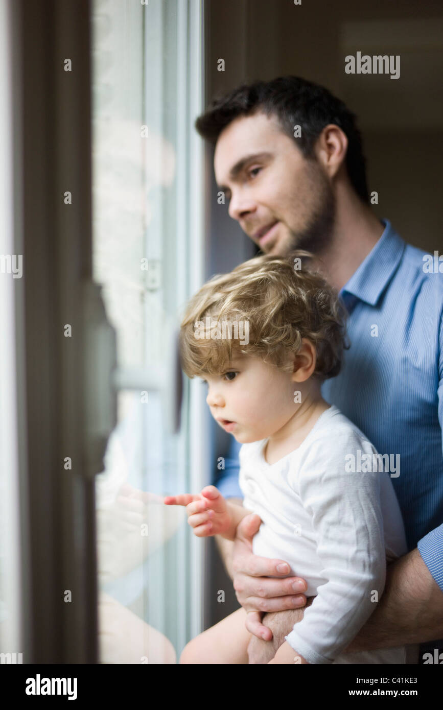 Father and toddler son looking out window, portrait Stock Photo - Alamy