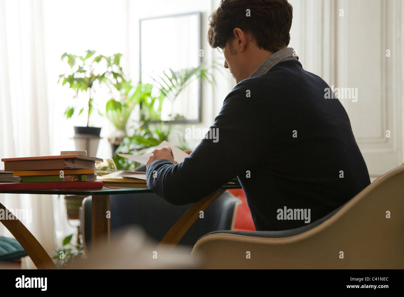 Man sitting at table reading Stock Photo - Alamy