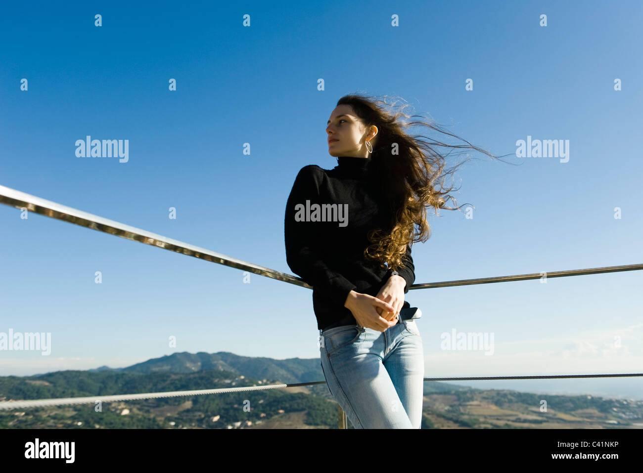 Woman leaning against railing, looking at view Stock Photo - Alamy