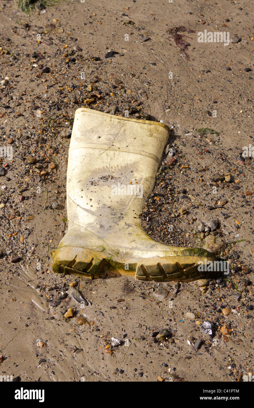 A lone yellow wellington (welly) boot discarded in the sand and mud at ...