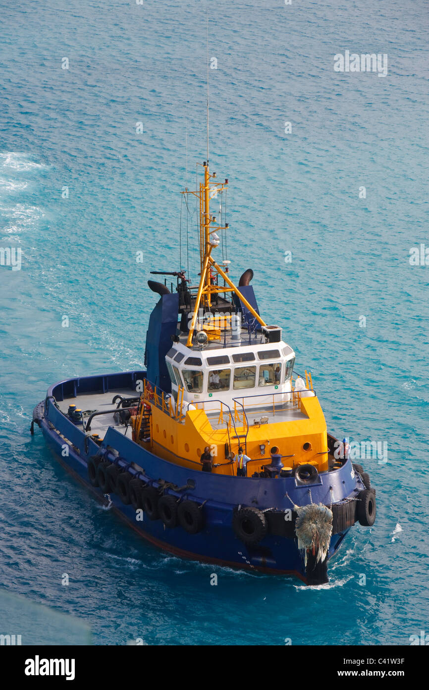 A yellow and blue tugboat in a calm aqua bay Stock Photo - Alamy