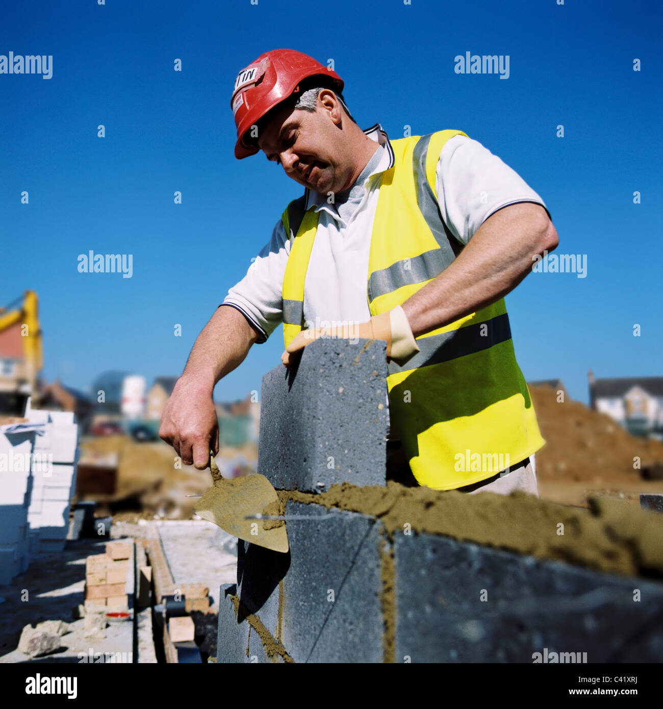 Bricklayer applying cement onto bricks Stock Photo - Alamy