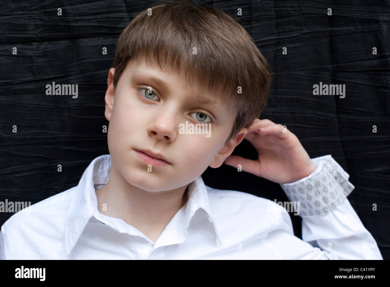 Portrait of a young boy with fair hair and blue eyes with his hand ...