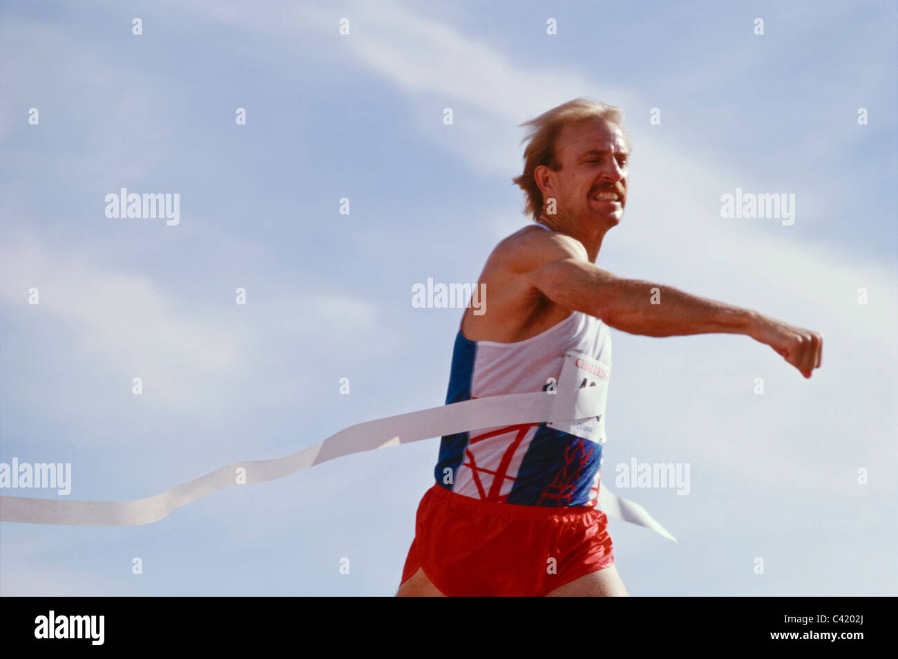 Male runner victorious at the finish line in a track race Stock Photo ...