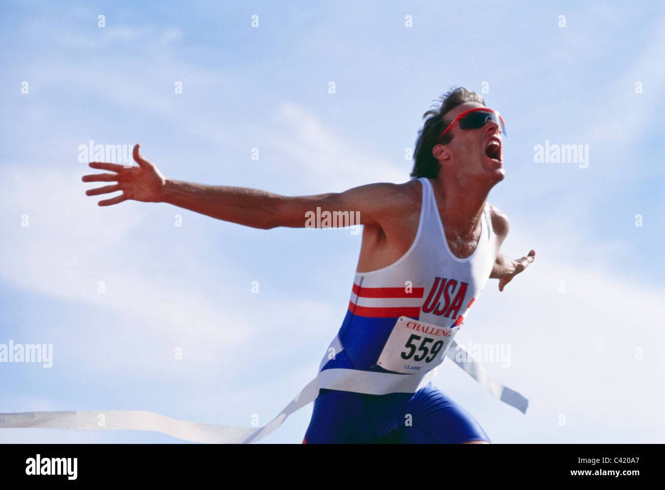 Male runner victorious at the finish line in a track race Stock Photo ...