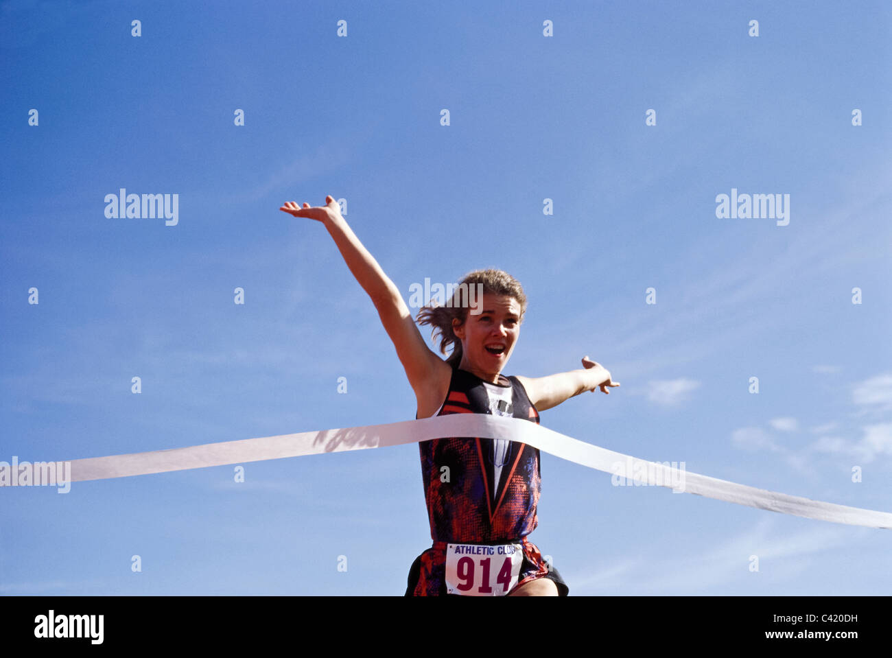 Female runner victorious at the finish line in a track race Stock Photo ...