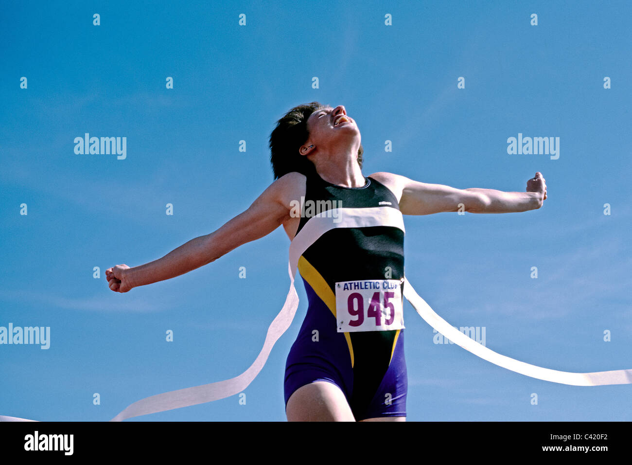 Female runner celebrates victory at the finish line Stock Photo - Alamy