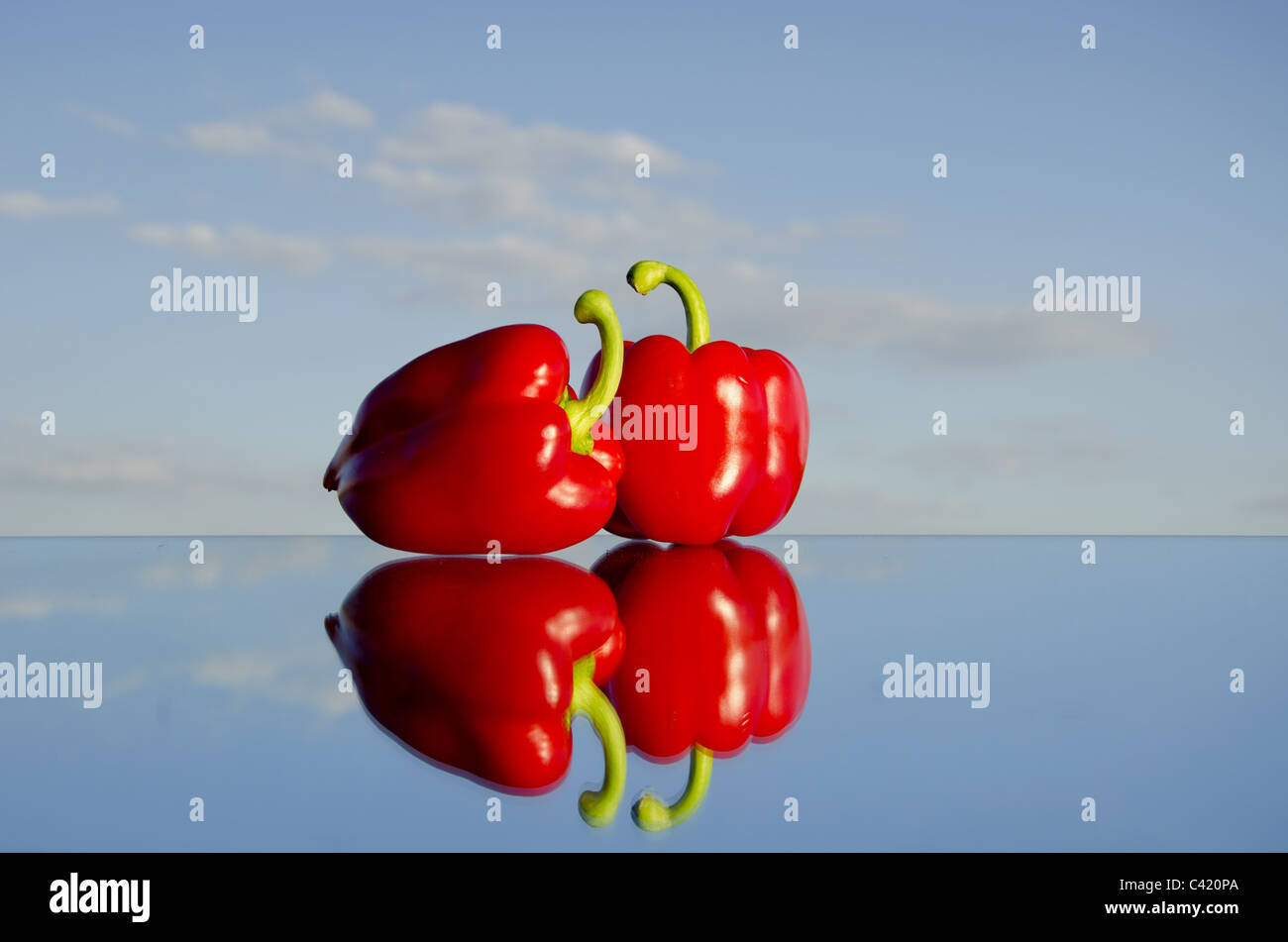 two red peppers on mirror and sky background Stock Photo - Alamy
