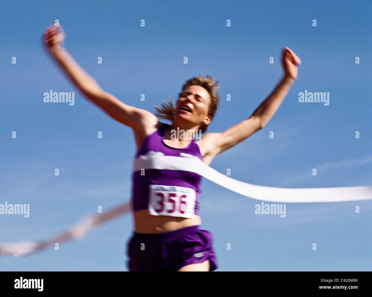 Female runner victorious at the finish line in a track race Stock Photo ...