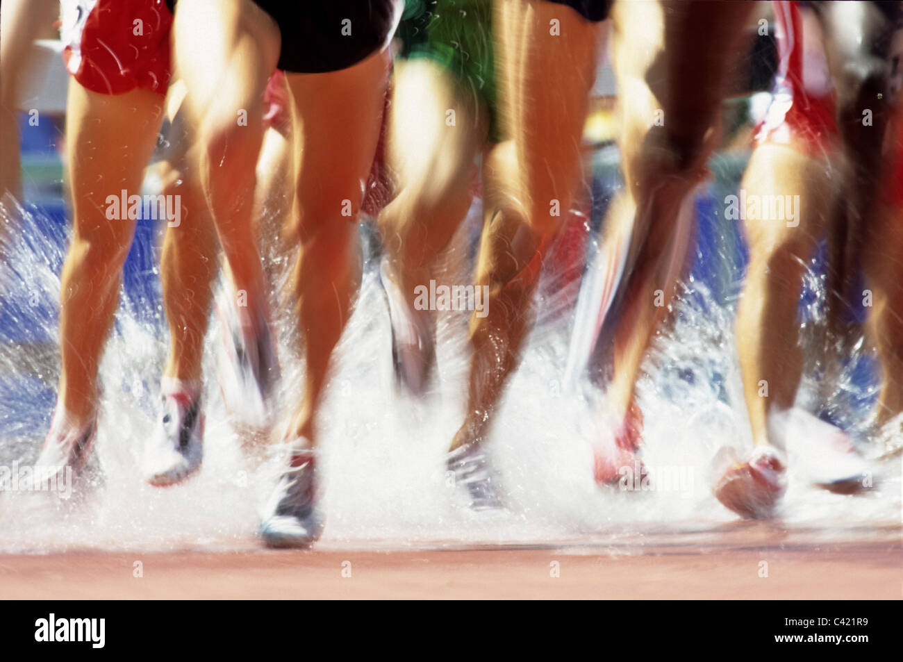 Detail of blurred action of runners legs splashing through the water ...