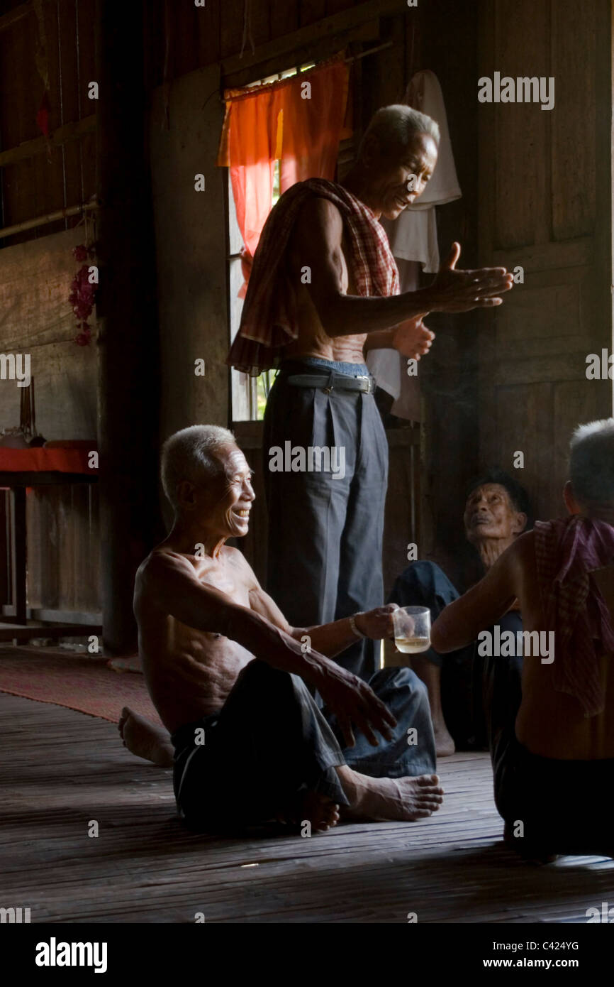 A group of poor elderly Khmer men are enjoying a conversation inside a ...