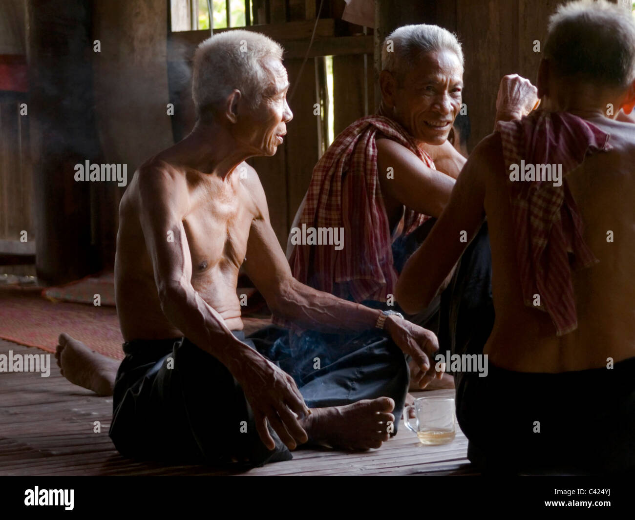 A group of poor elderly Khmer men are enjoying a conversation inside a ...
