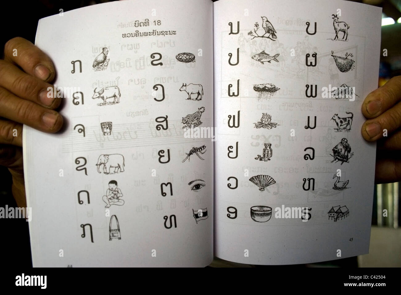 A man is holding an official Lao government primary school textbook at ...