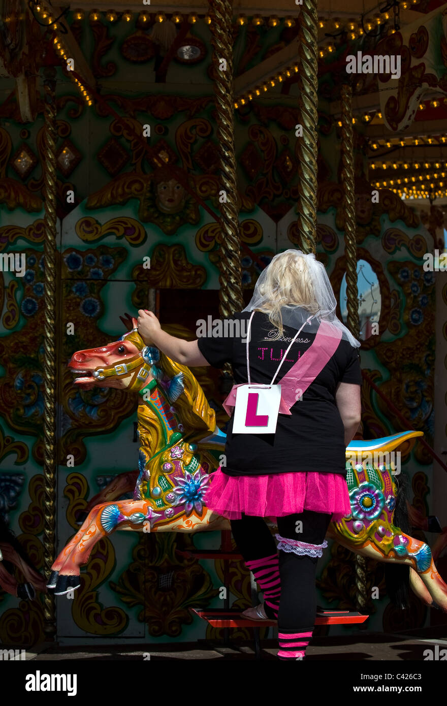 A woman from a hen party climbing on to a carousel horse on Brighton ...