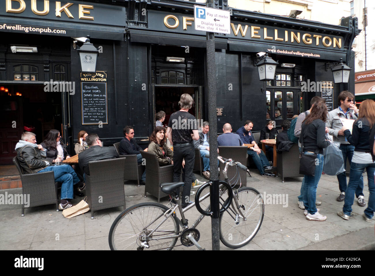 Crowd sitting outstide the Duke of Wellington pub on Portobello Road on ...